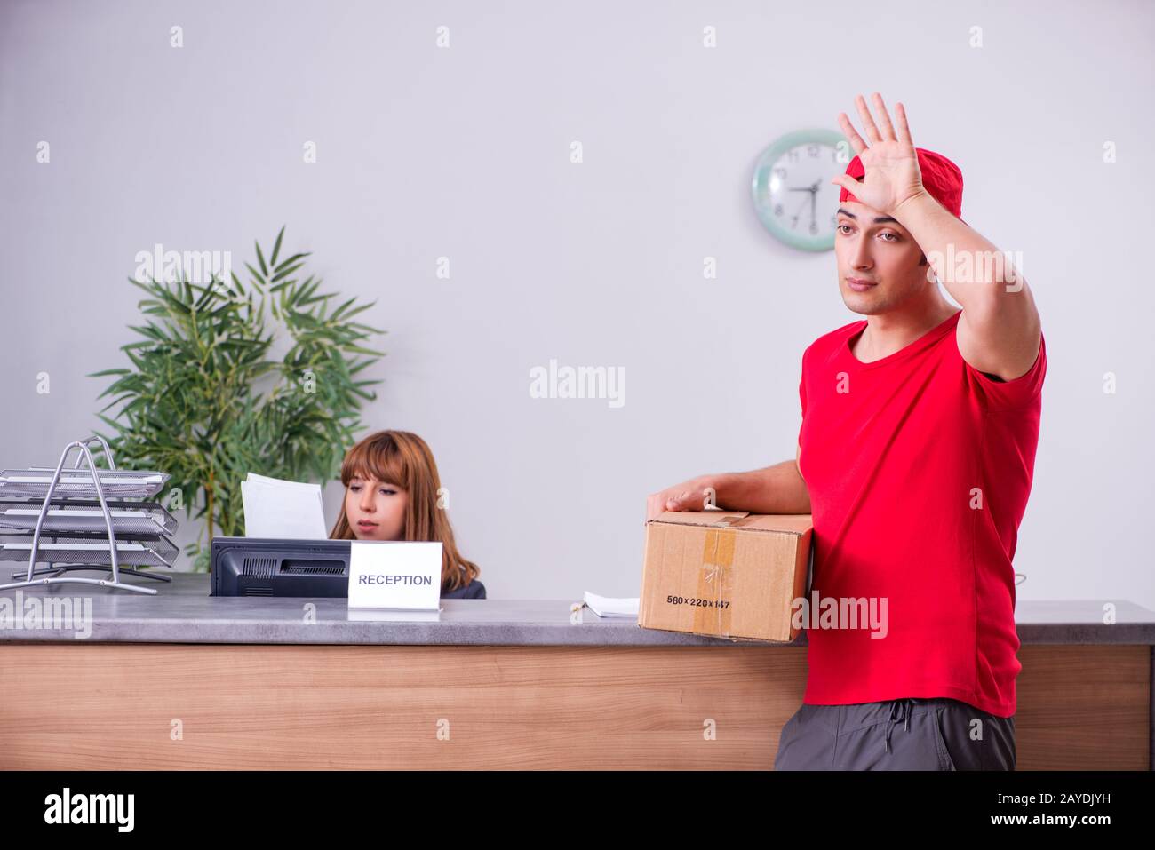 Young male courier delivering box to hotel's reception Stock Photo - Alamy