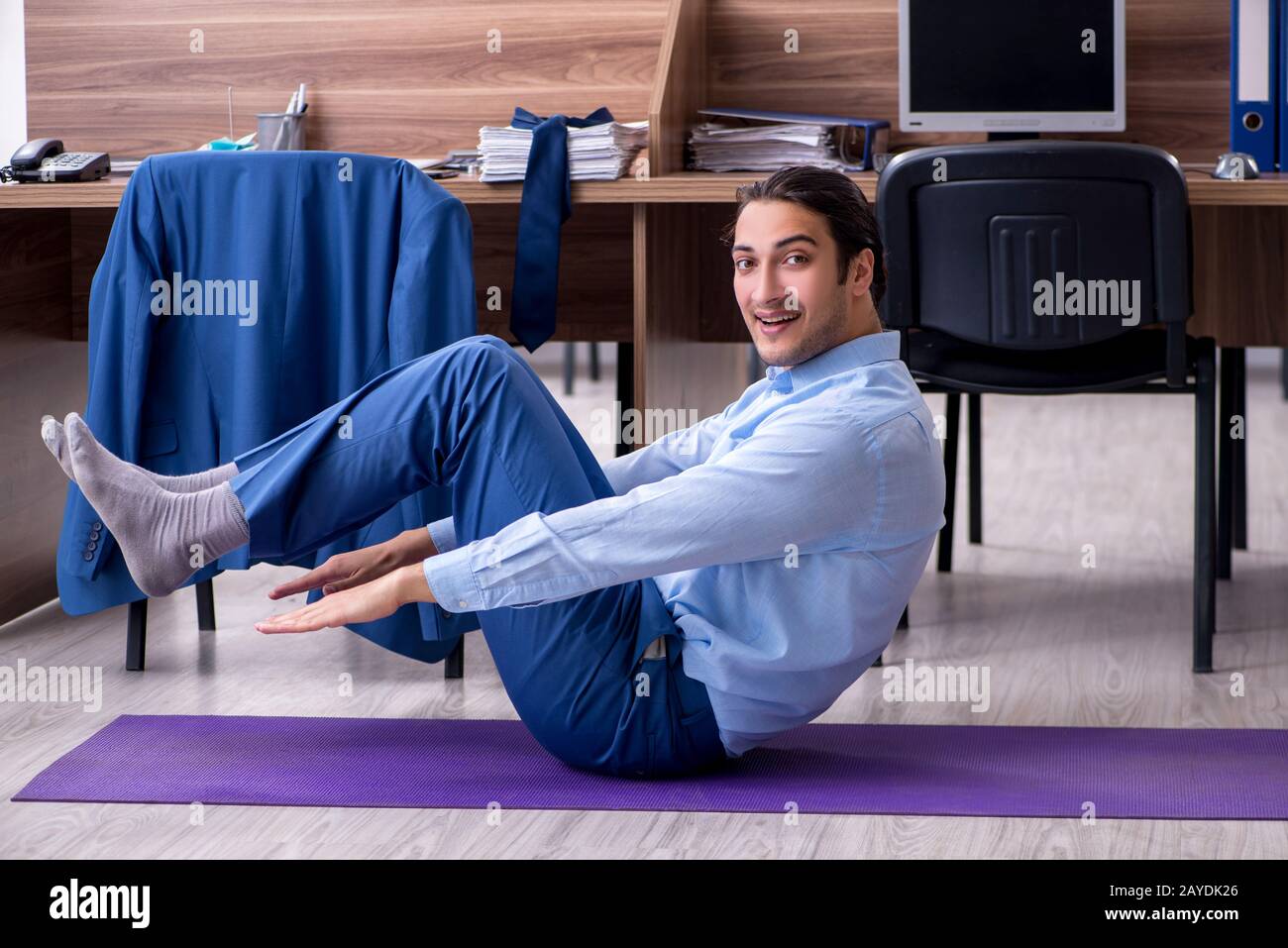 Young handsome businessman doing exercises at workplace Stock Photo - Alamy
