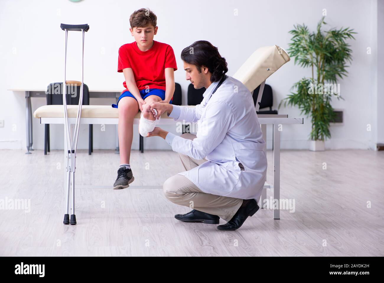 Leg injured boy visiting young doctor traumatologist Stock Photo - Alamy