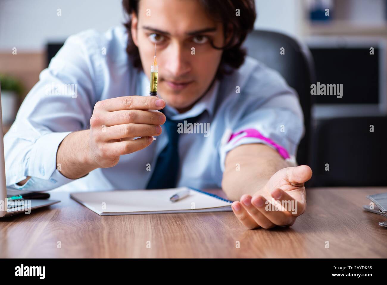 Young man having problems with narcotics at workplace Stock Photo - Alamy