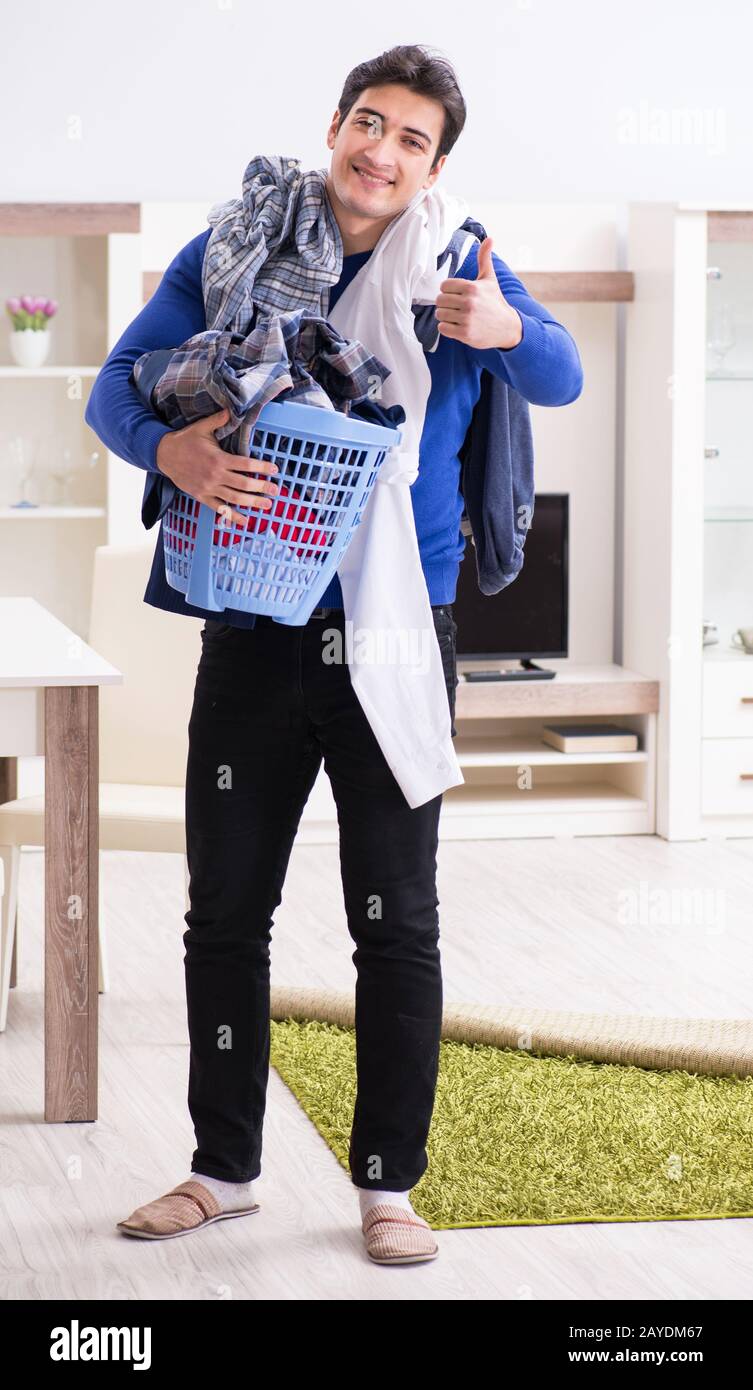 Young man collecting dirty clothing for laundry Stock Photo - Alamy
