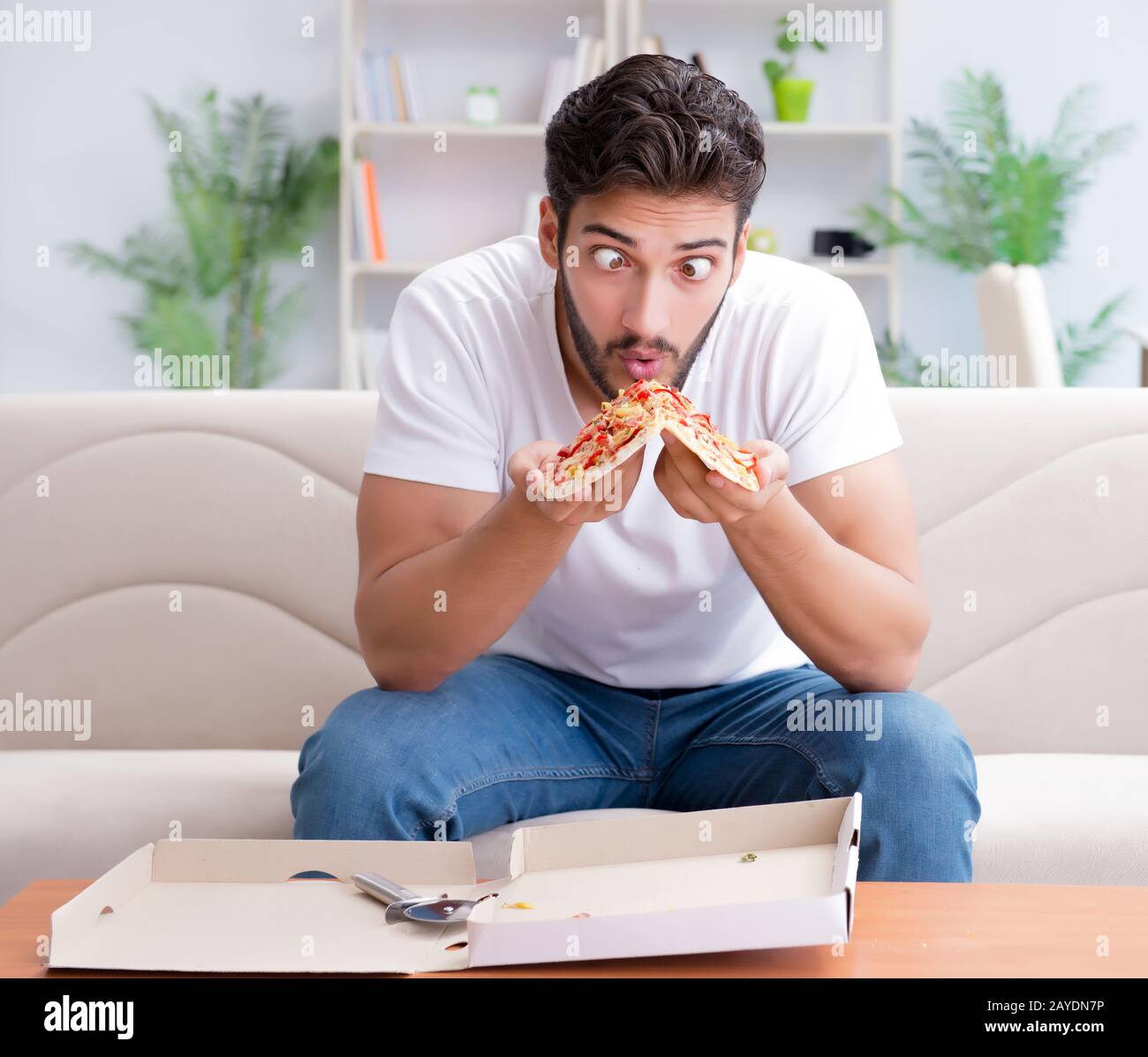 Man eating pizza having a takeaway at home relaxing resting Stock Photo ...