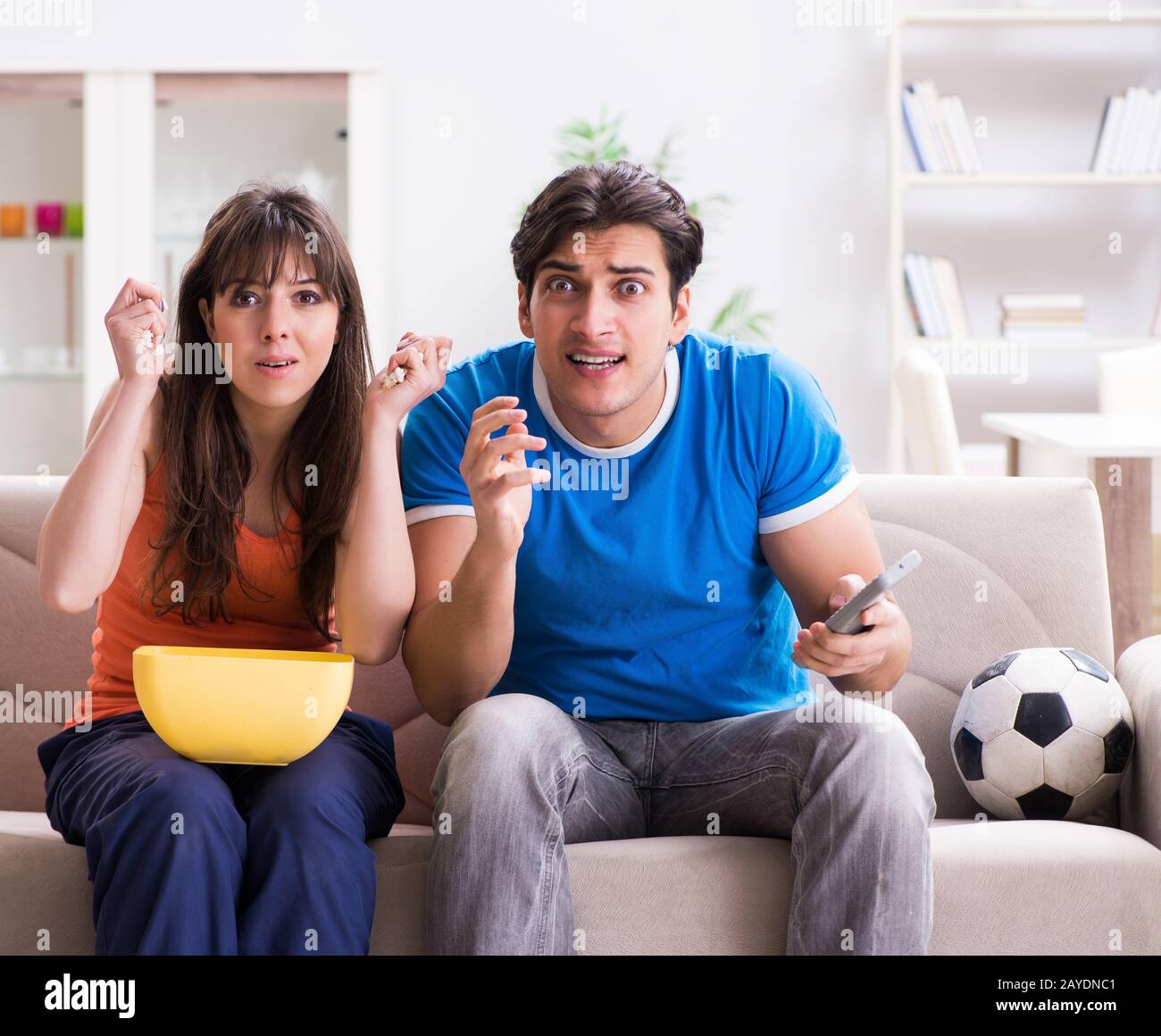 Young man watching football with his wife at home Stock Photo - Alamy