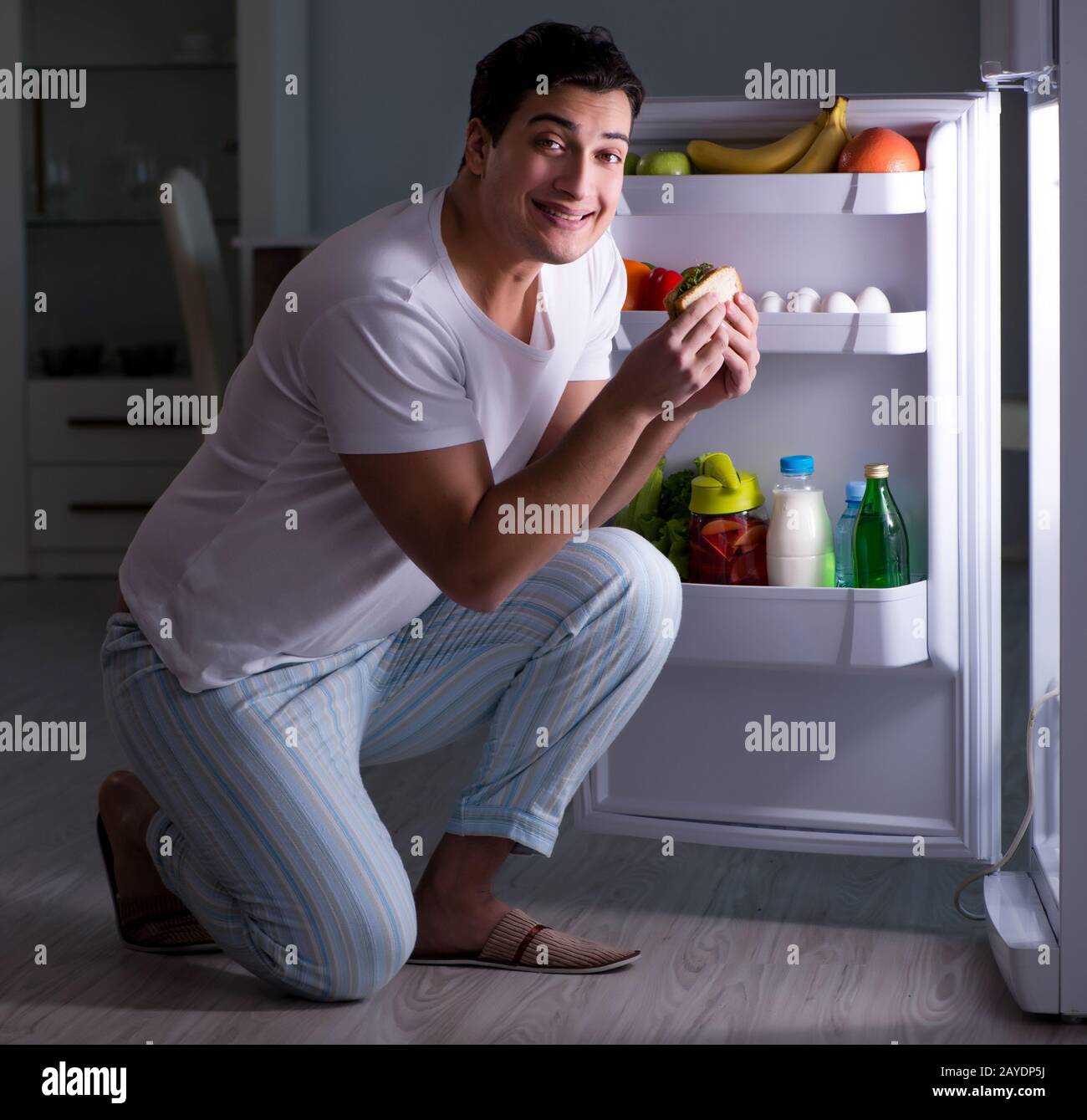 Man at the fridge eating at night Stock Photo - Alamy