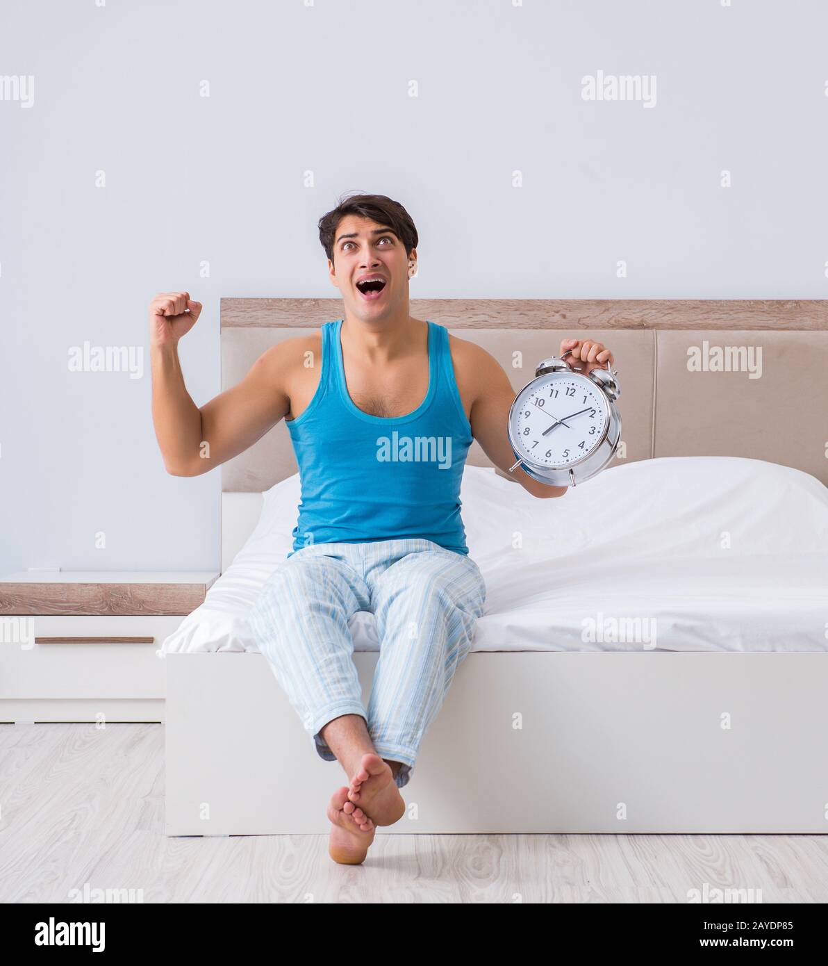 Young man waking up in bed Stock Photo - Alamy