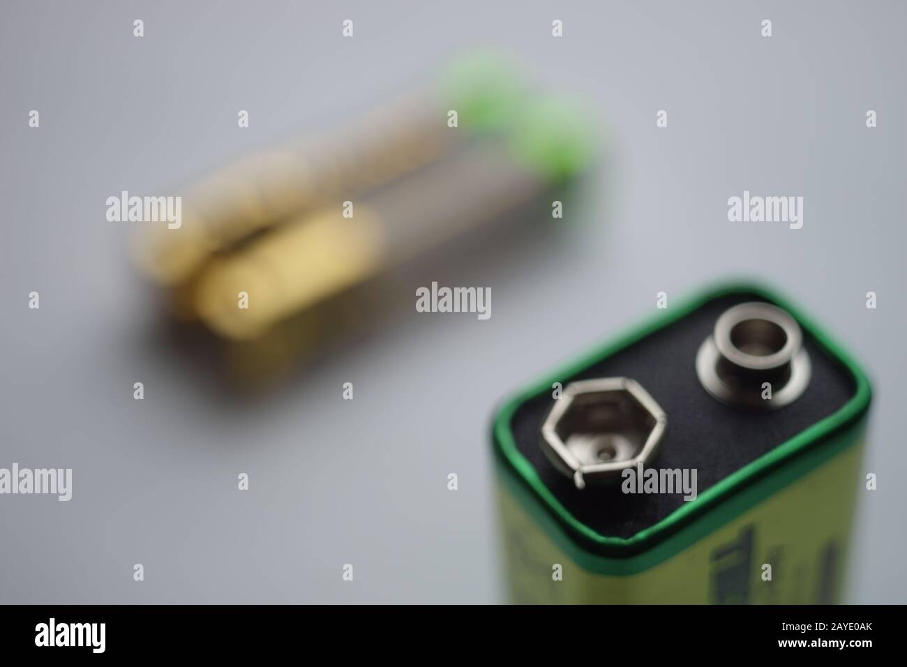 Green alkaline battery close-up, two finger batteries on a blurred ...