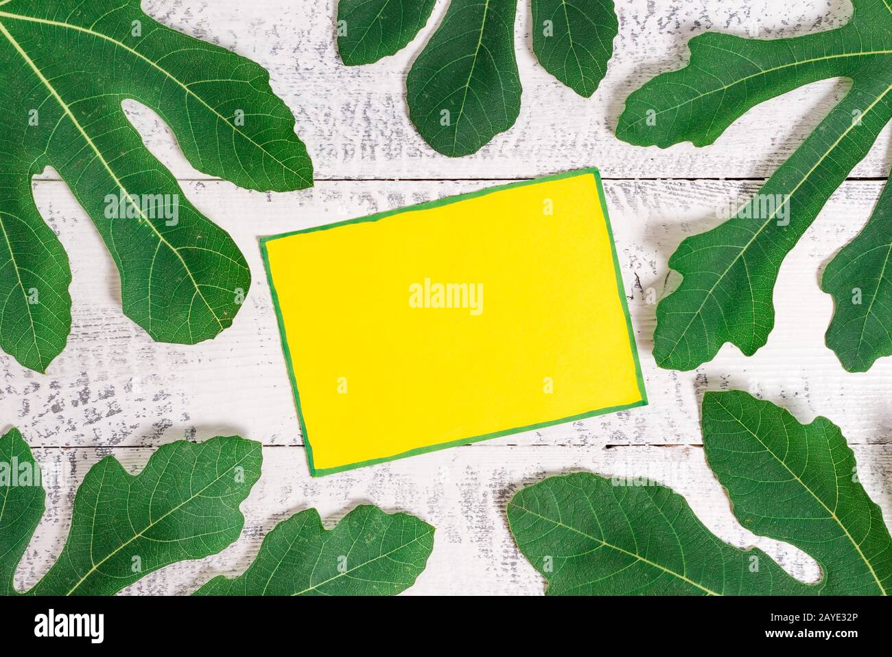 Notepaper placed above classic wooden table between green leaves ...