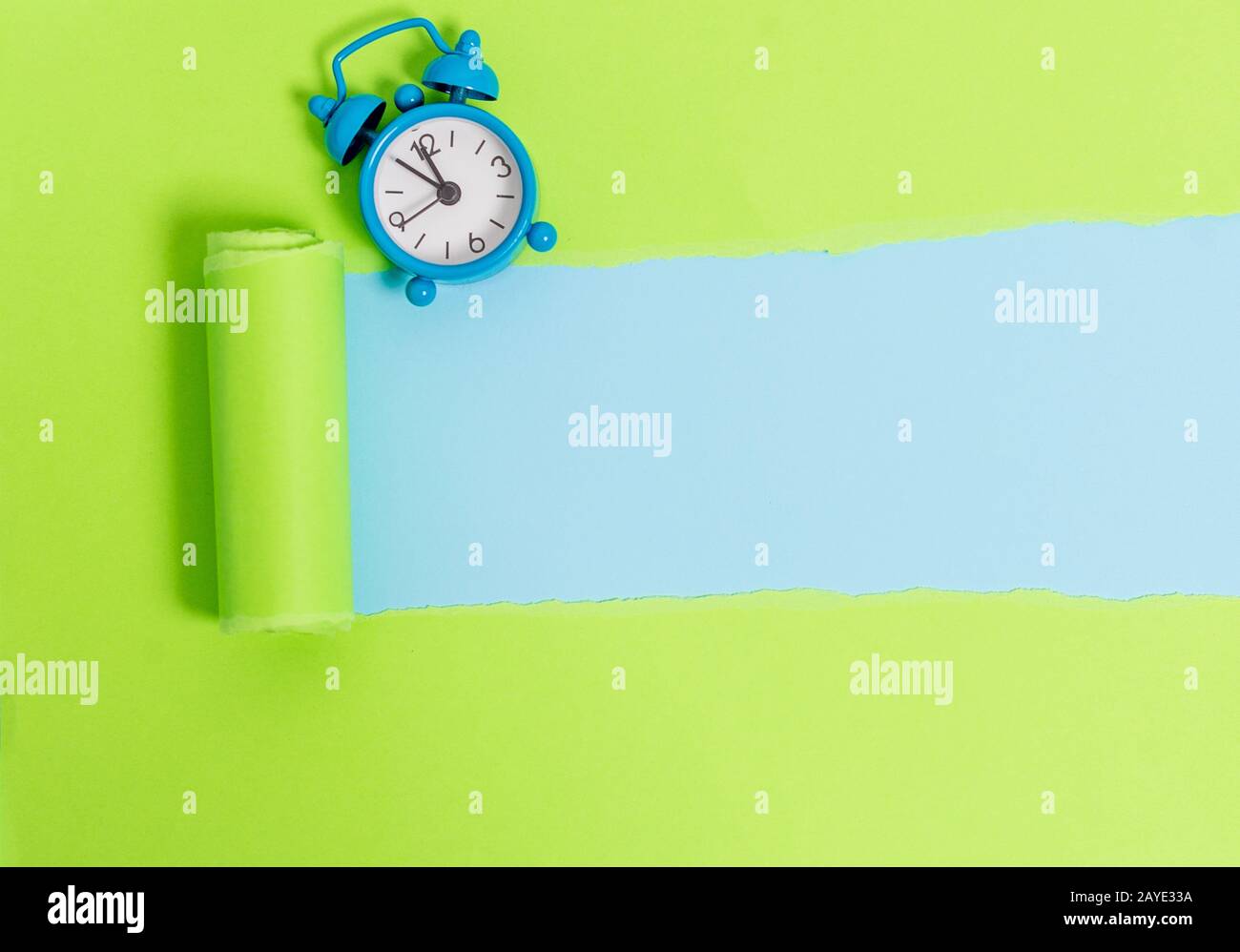 Ripped cardboard with a mini alarm clock placed above a soft colour ...