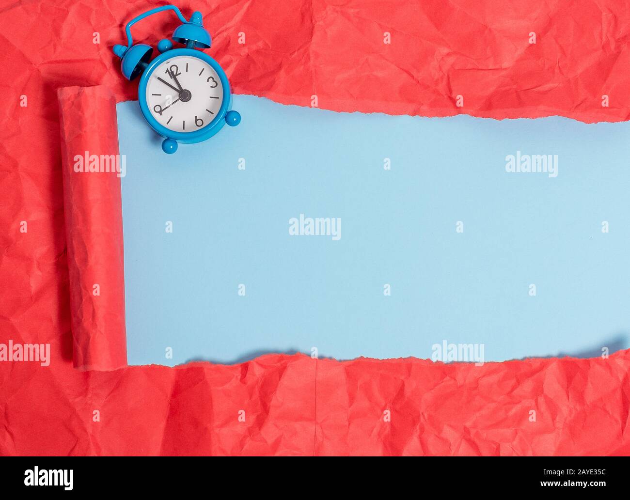 Ripped cardboard with a mini alarm clock placed above a soft colour ...