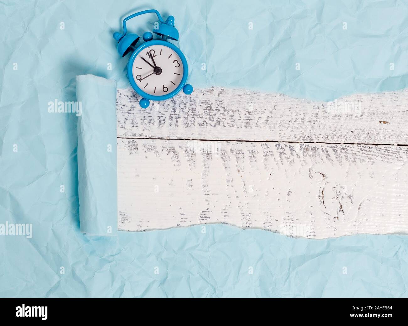 Ripped cardboard with a mini alarm clock placed above a wooden classic ...