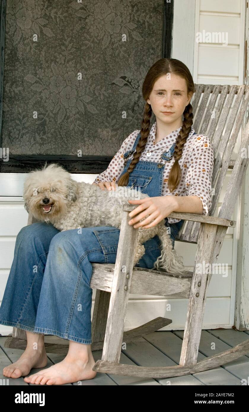 A young, bare-footed girl wearing overalls with freckles and pigtails ...