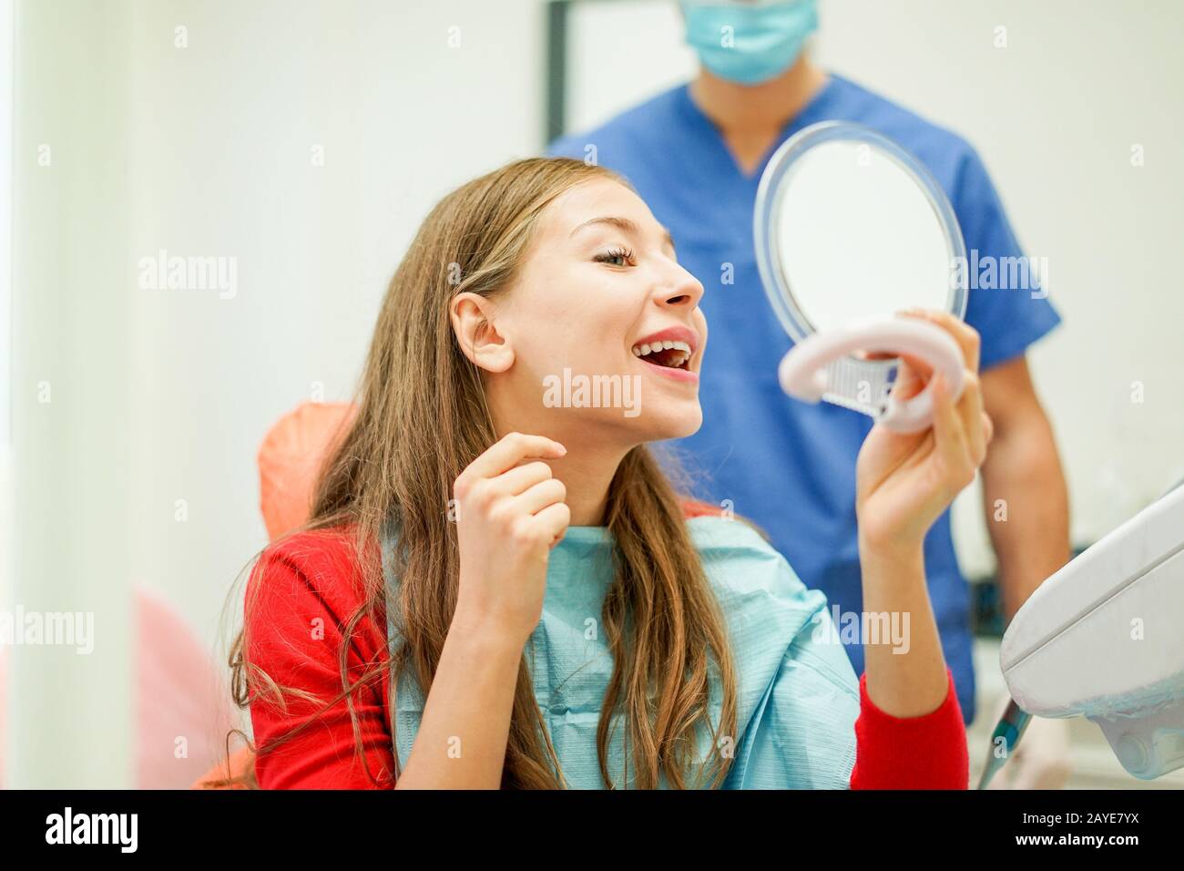 Young woman checking their teeth at mirror after dental treatment ...