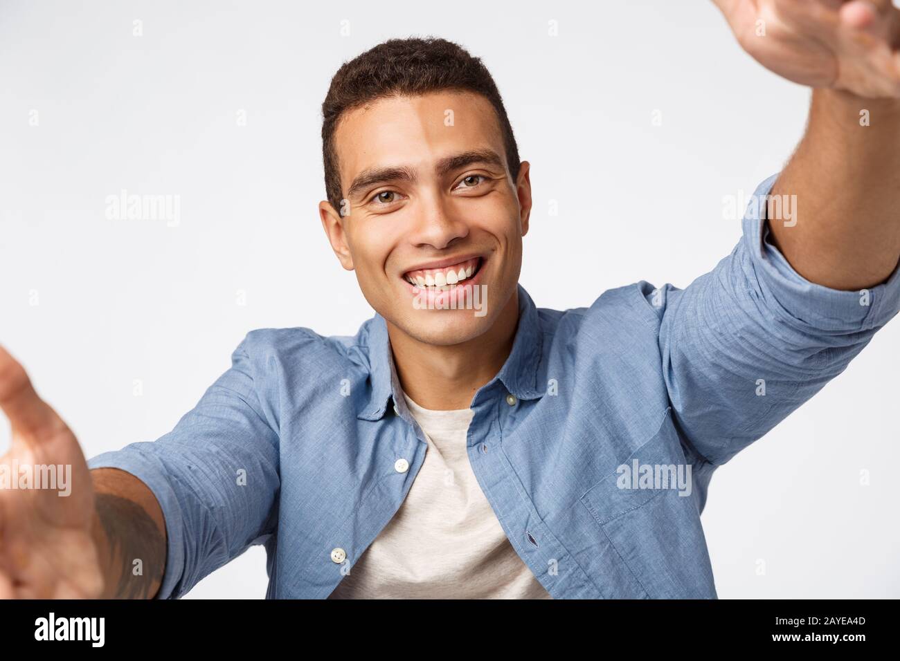 Friendly cheerful masculine guy in casual outfit, holding camera both ...