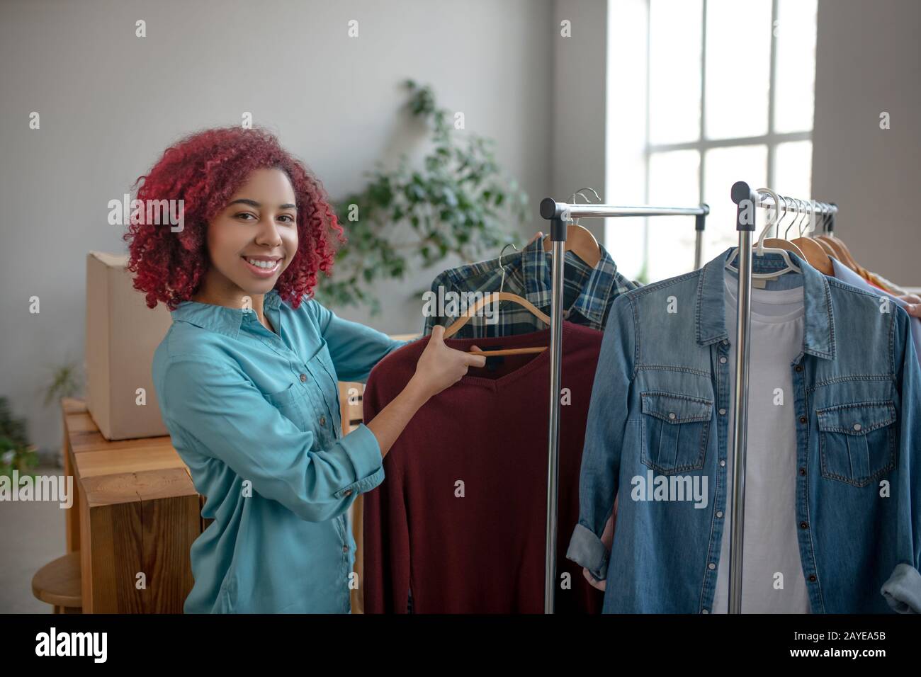 Beautiful young girl near the rack with clothes Stock Photo - Alamy