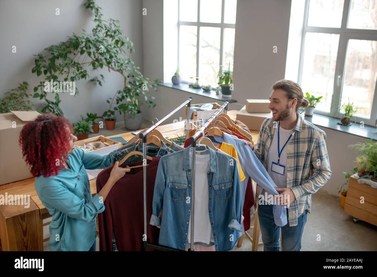 Young girl and man sorting clothes on trempels Stock Photo - Alamy