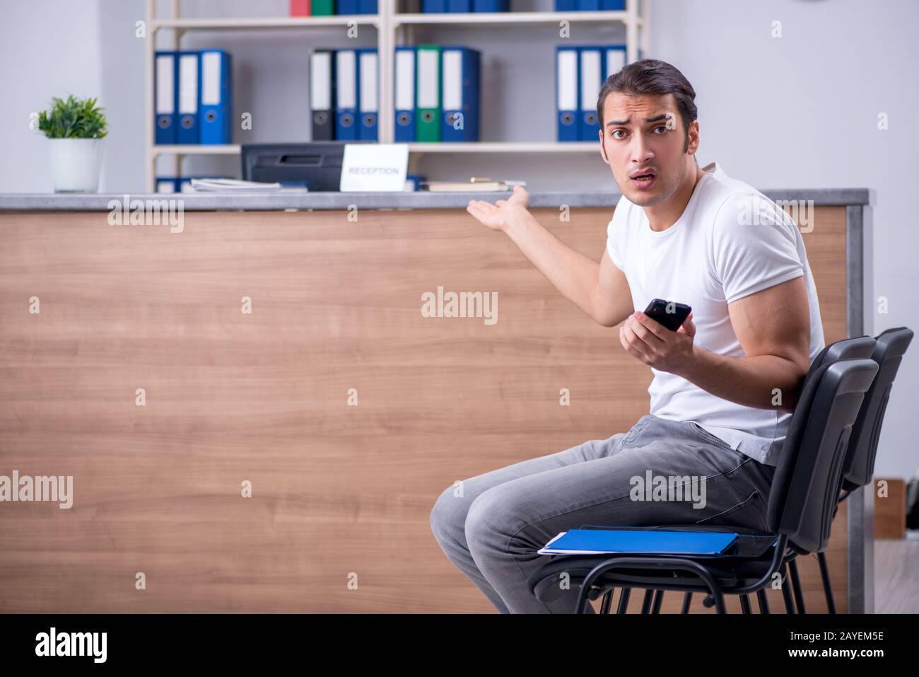 Young man at hospital reception desk Stock Photo - Alamy