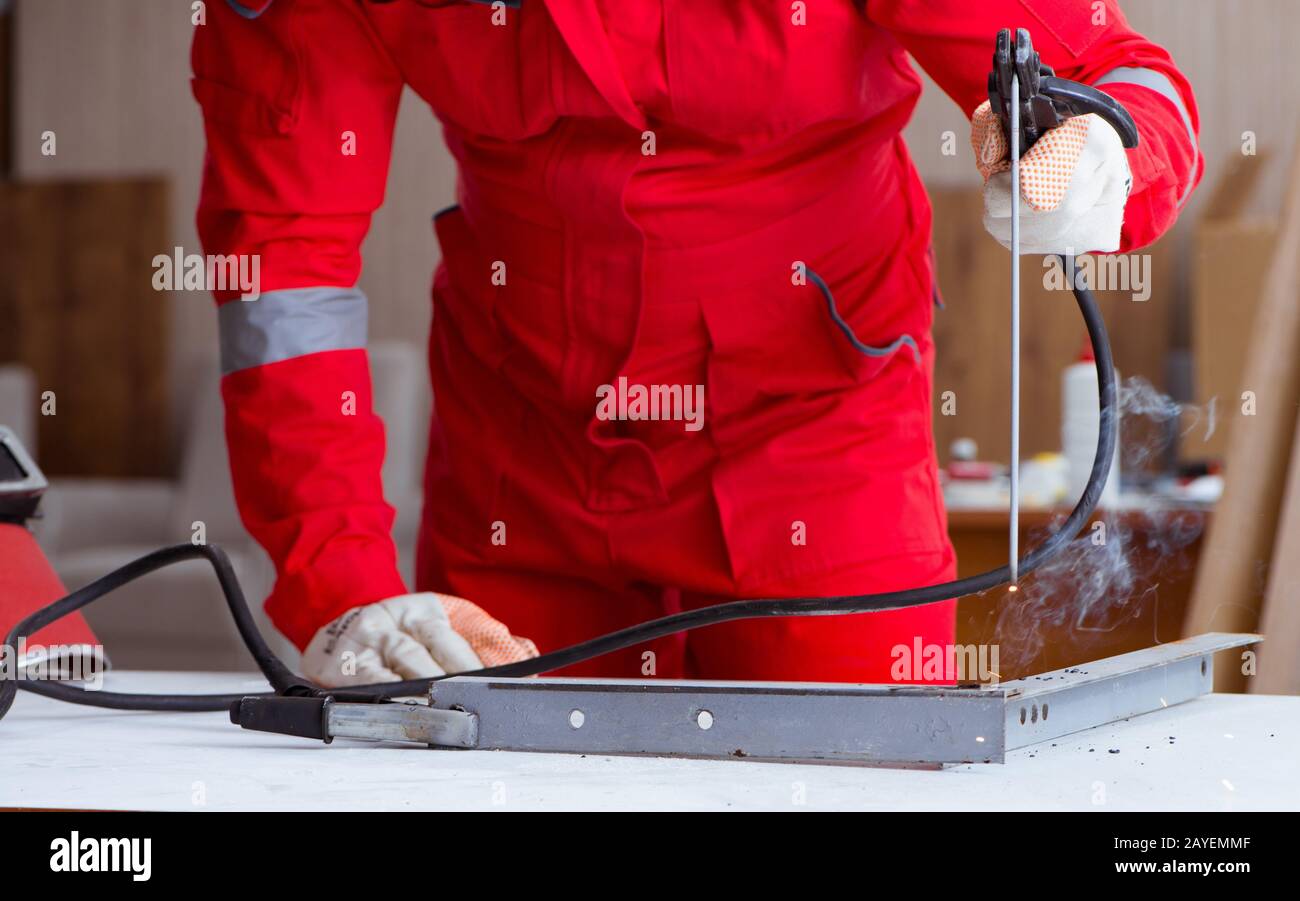 Young repairman with a welding gun electrode and a helmet weldin Stock ...
