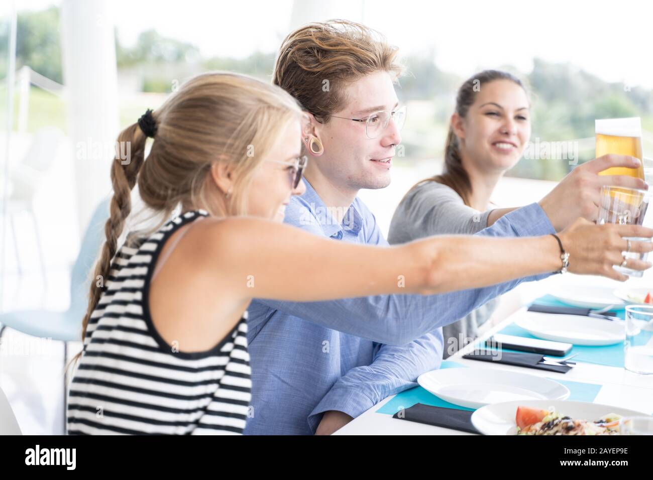 group of young people sitting at a white table with empty plates ...