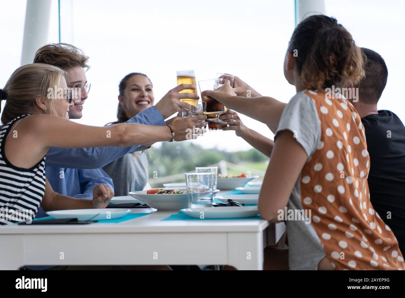 group of young people sitting at a white table with empty plates ...