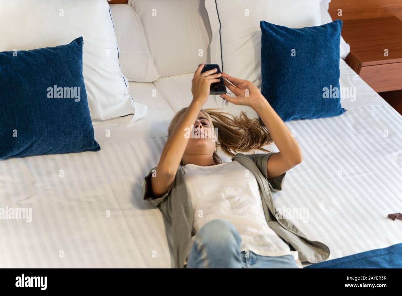 girl looks at the cell phone stretched out on the bed Stock Photo - Alamy