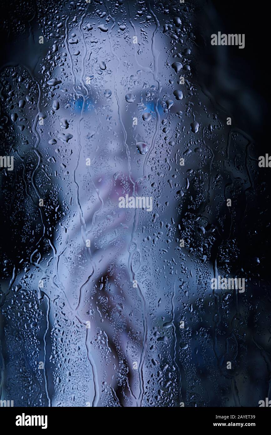 Sad young woman behind the window glass with raindrops Stock Photo - Alamy