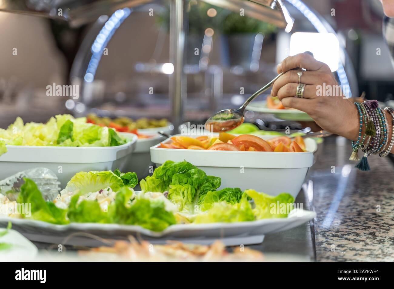 Stock photo of a hand with ring picking up food from a salad plate at a ...
