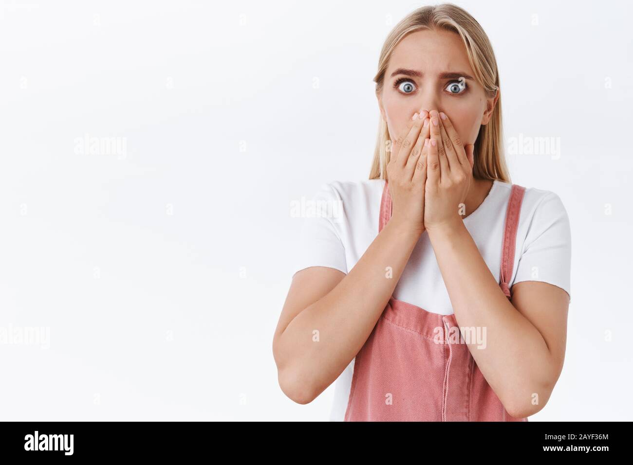 Shocked blond cute girl gasping and cover mouth as stare camera ...