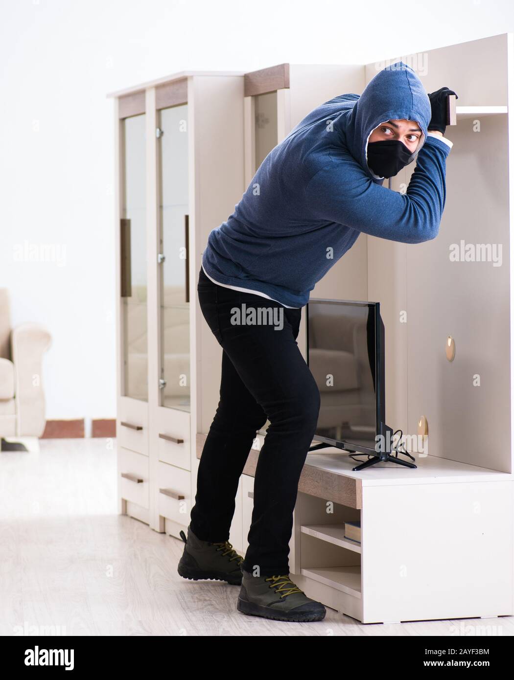 Man burglar stealing tv set from house Stock Photo - Alamy