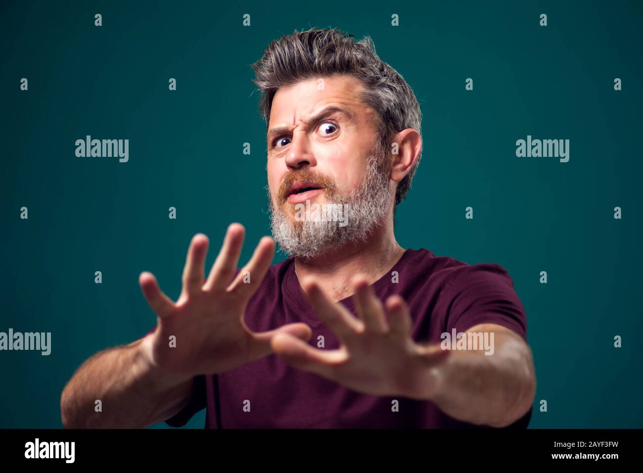 A portrait of scared bearded man in red t-shirt. People and emotions ...