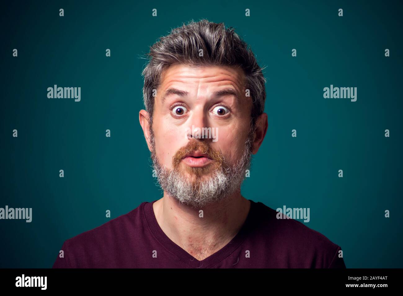 A portrait of bearded surprised man in red t-shirt. People and emotions ...