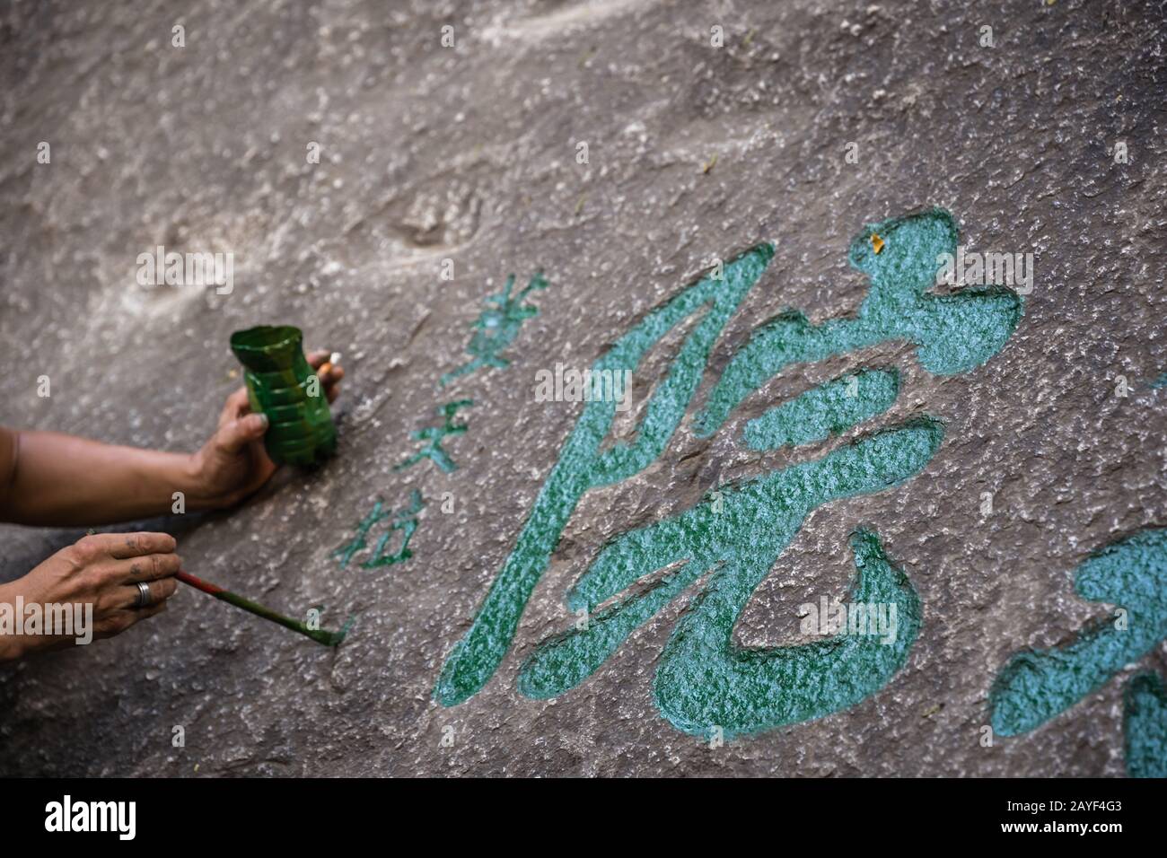 Man painting chinese calligraphy characters on a rock Stock Photo - Alamy