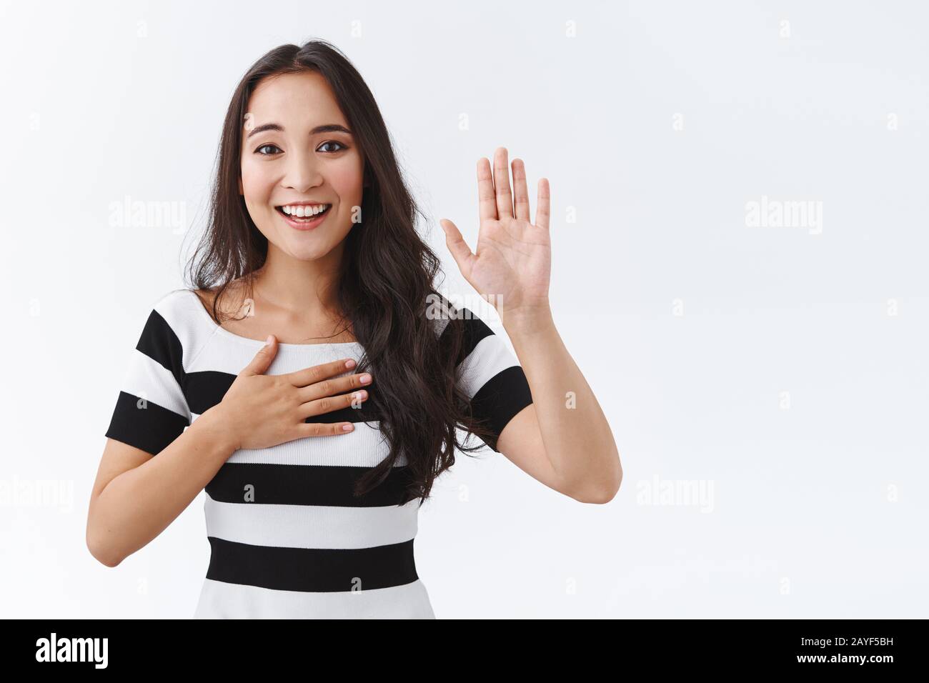 Charming east-asian woman in striped t-shirt making promise, raise one ...