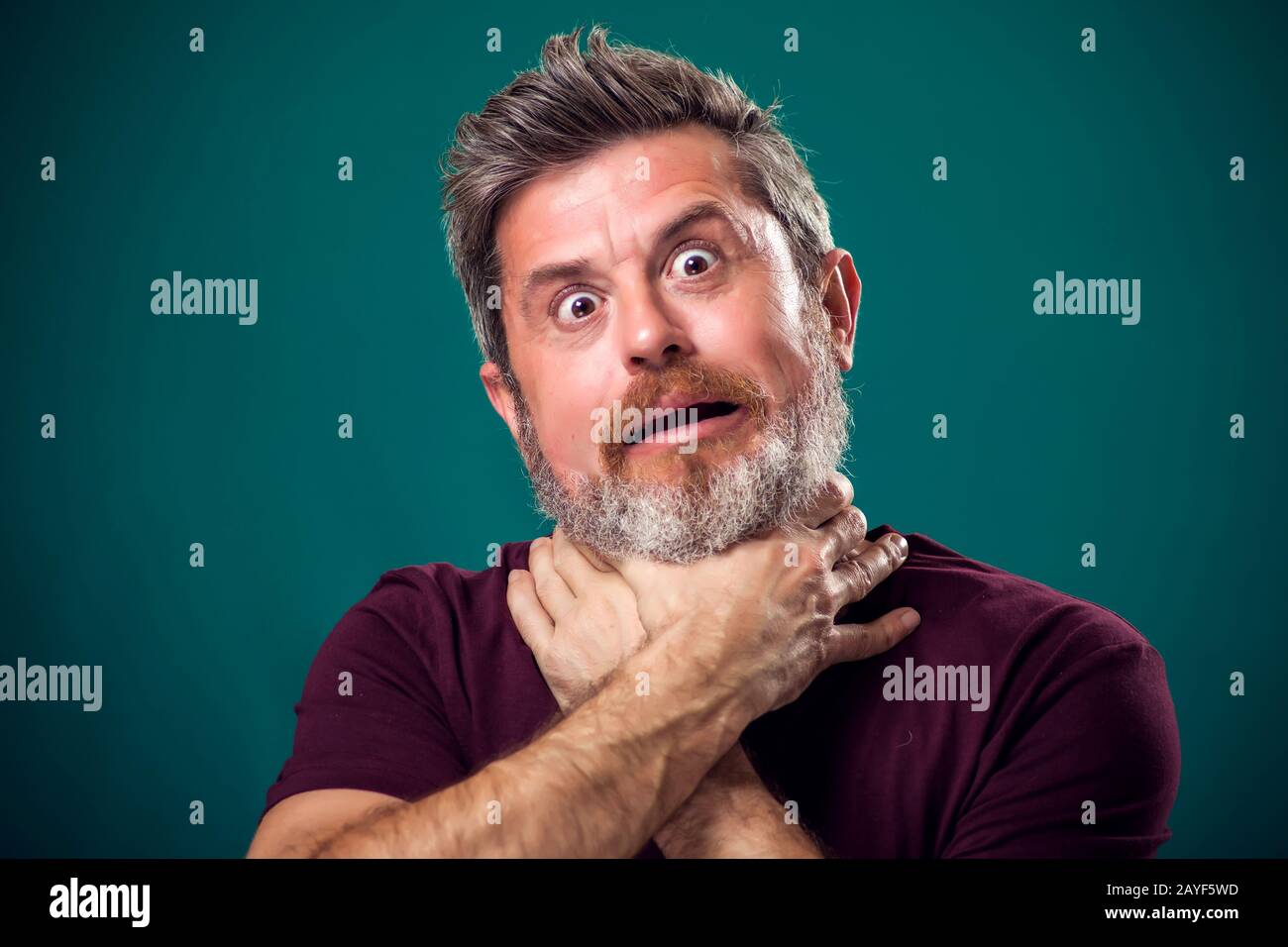 A portrait of bearded man in red t-shirt choking himself. People and ...
