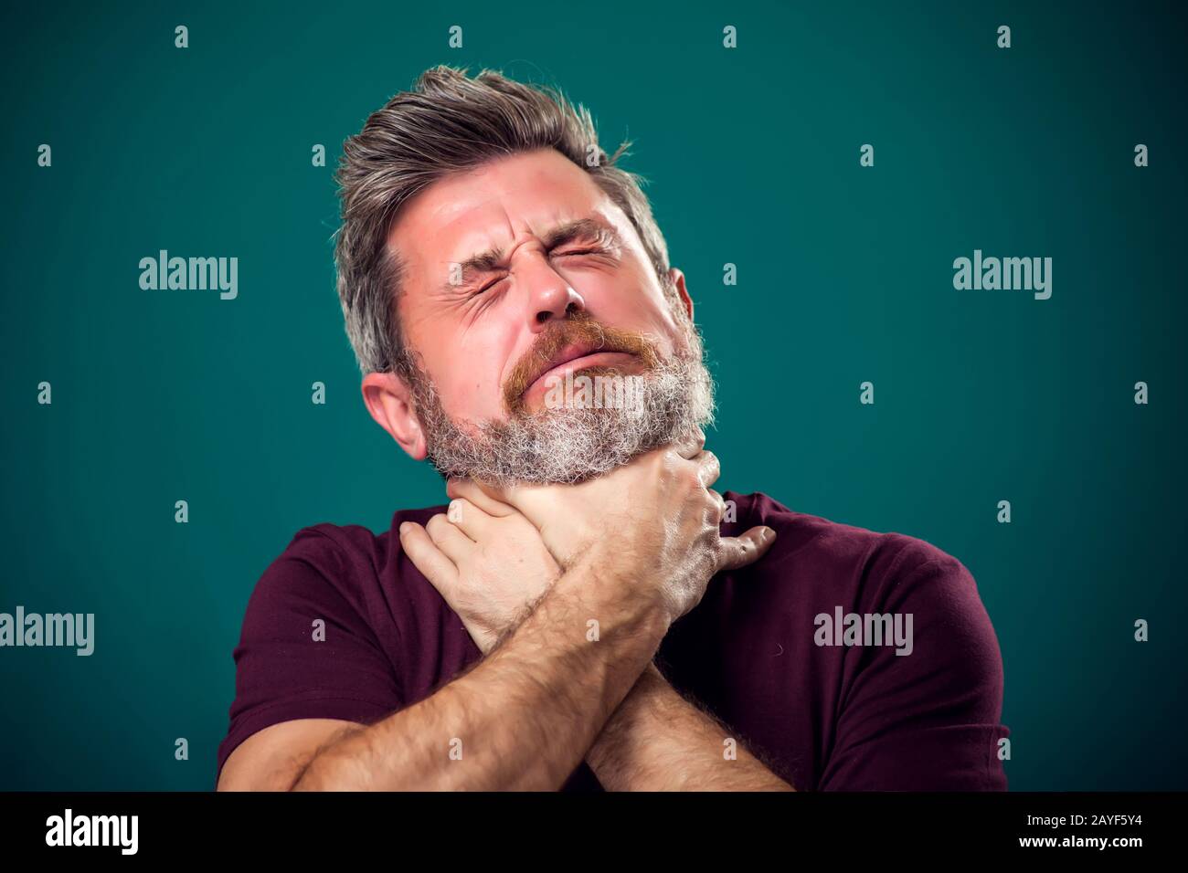 A portrait of bearded man in red t-shirt choking himself. People and ...