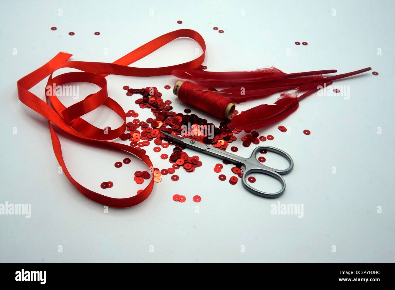 Red sequins, spool of red thread, needle, scissors, red ribbon and red ...
