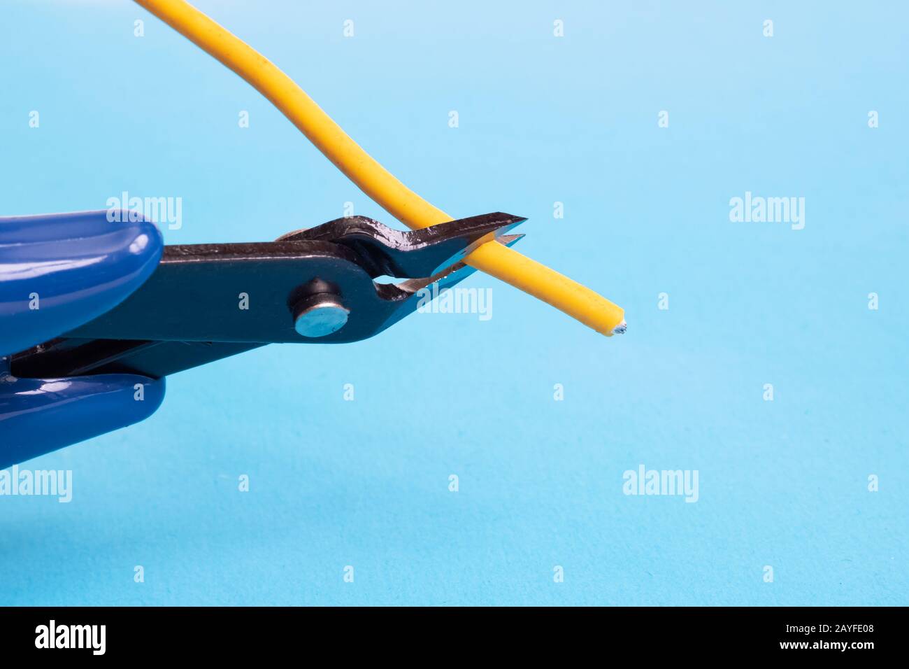 Blue wire cutter cuts yellow wire on blue background close up Stock ...