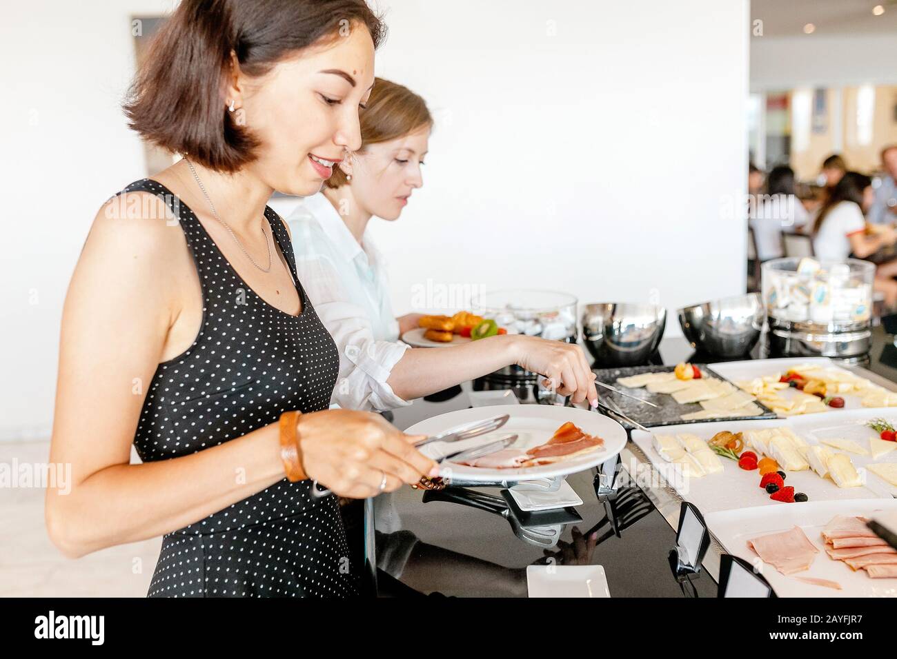 Woman picking food at all you can eat buffet in breakfast at hotel ...