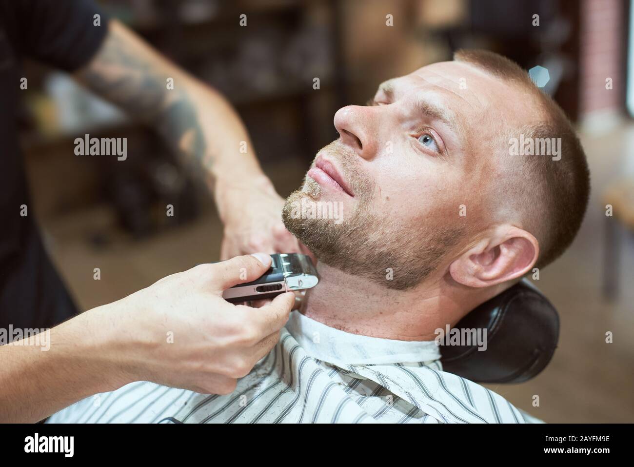 Getting perfect shape. Close-up side view of young bearded man getting ...