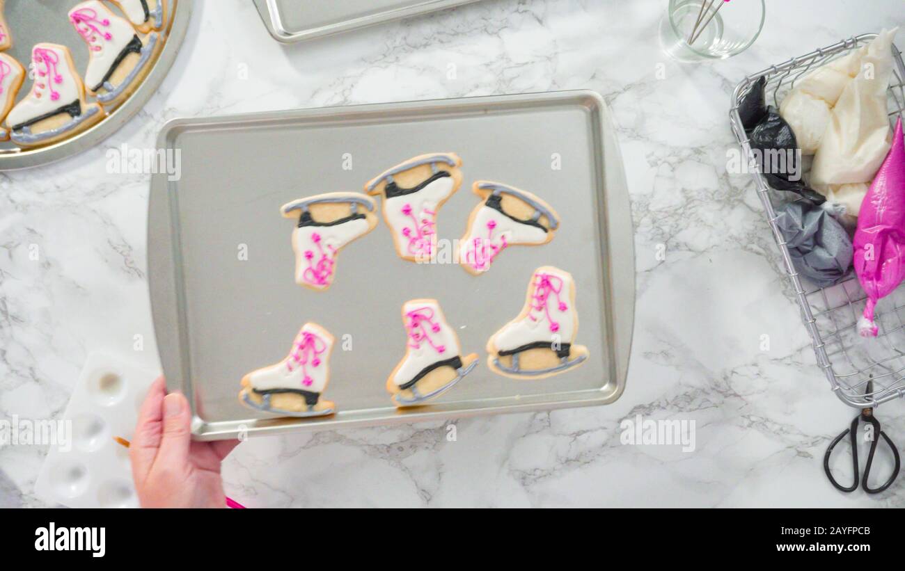 Flat lay. Brushing edible glitter on iced figure skate sugar cookies ...