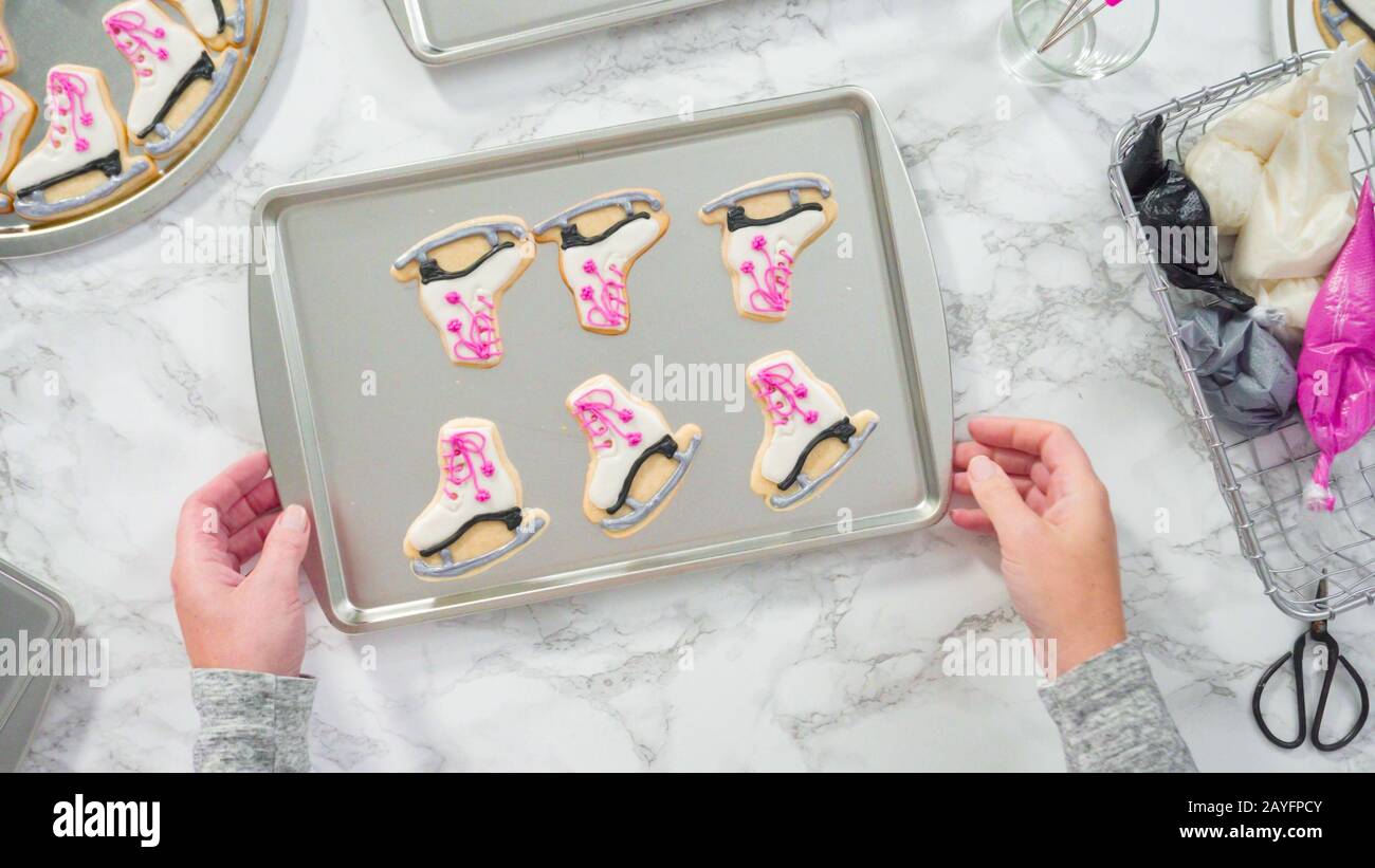 Flat lay. Brushing edible glitter on iced figure skate sugar cookies ...