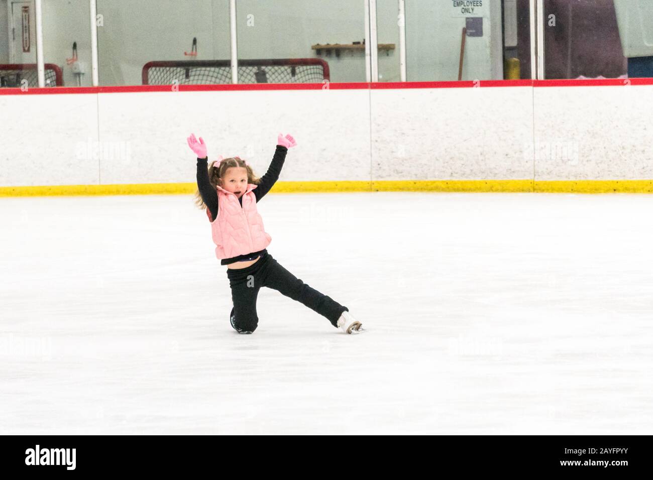 Little girl practicing figure skating moves on the indoor ice rink ...