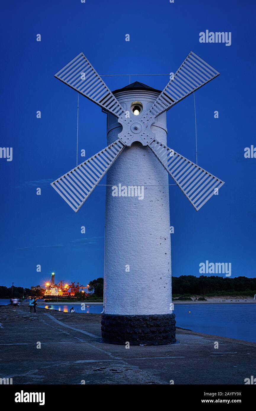 Lighthouse in the evening on the Baltic Sea with windmill wings in ...