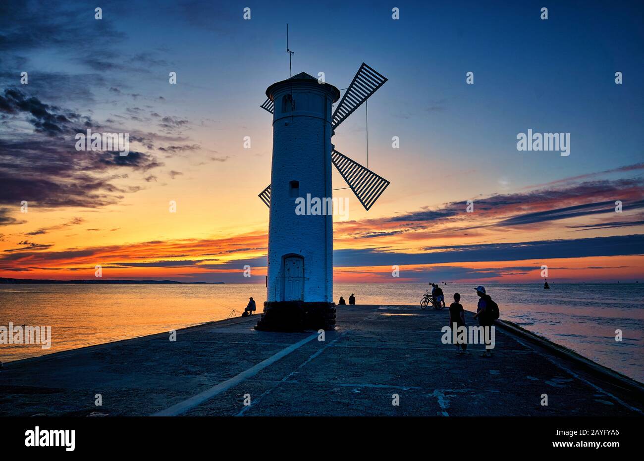 Tourists at the windmill shaped lighthouse on the Baltic Sea in ...