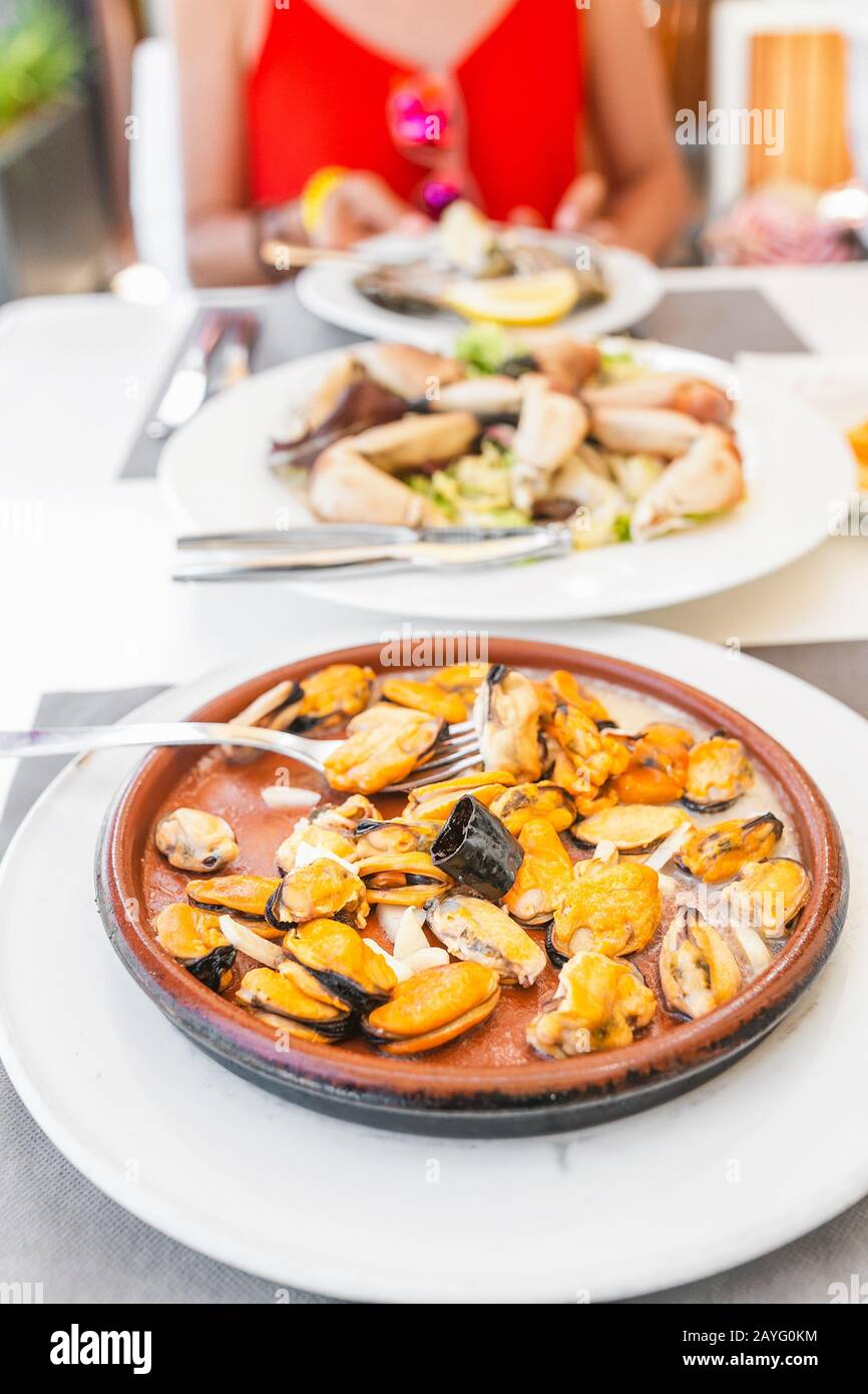 Woman eating shellfish mussels in seafood restaurant Stock Photo - Alamy