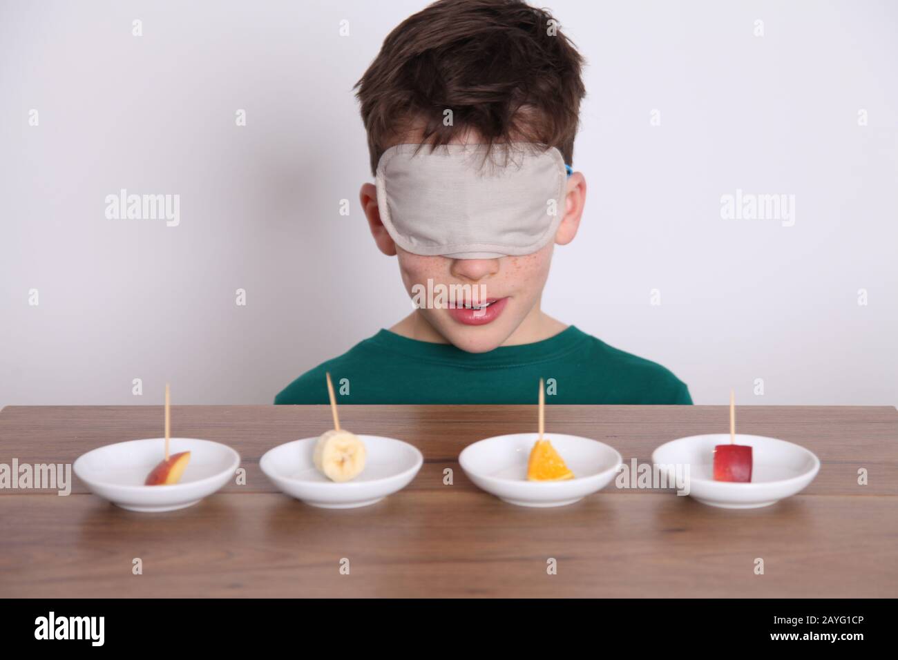 A dark haired boy of 8yrs old takes part in a blindfold taste test ...