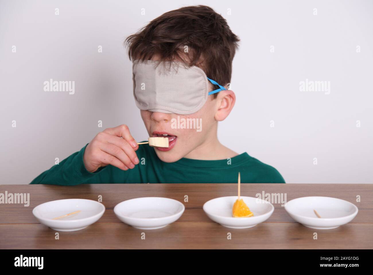 A dark haired boy of 8yrs old takes part in a blindfold taste test ...