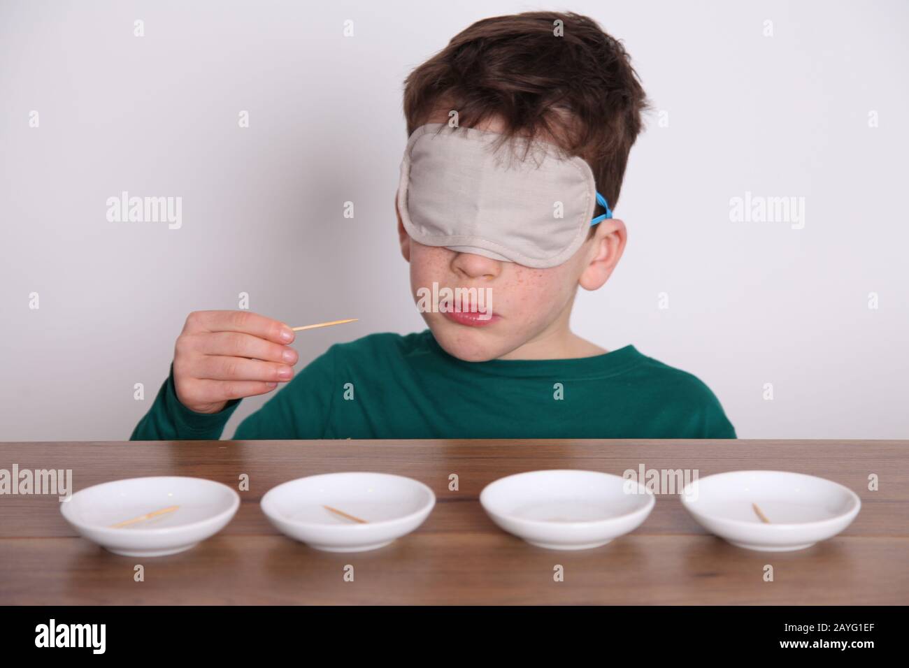 A dark haired boy of 8yrs old takes part in a blindfold taste test ...