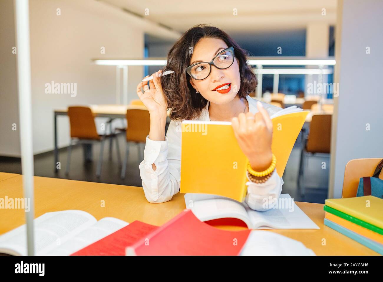 Surprised Woman reading Book in library Stock Photo - Alamy