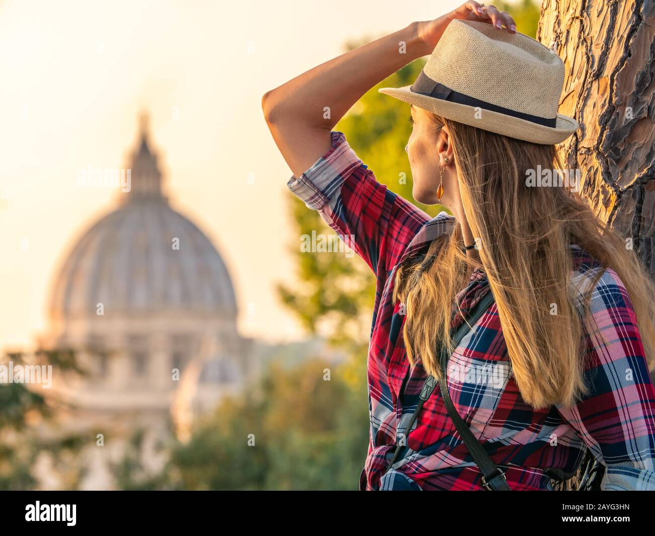 Beautiful young blonde woman with long hair leaning on a tree in ...