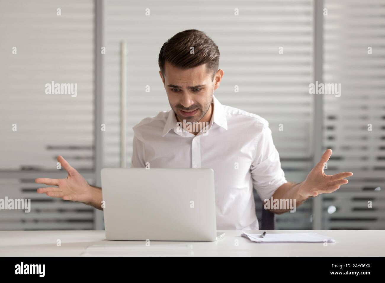 Confused male worker having laptop problems in office Stock Photo - Alamy